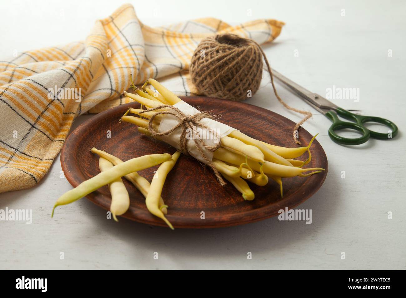 Clay plate with several pods and bunch of raw yellow pods of haricot ...