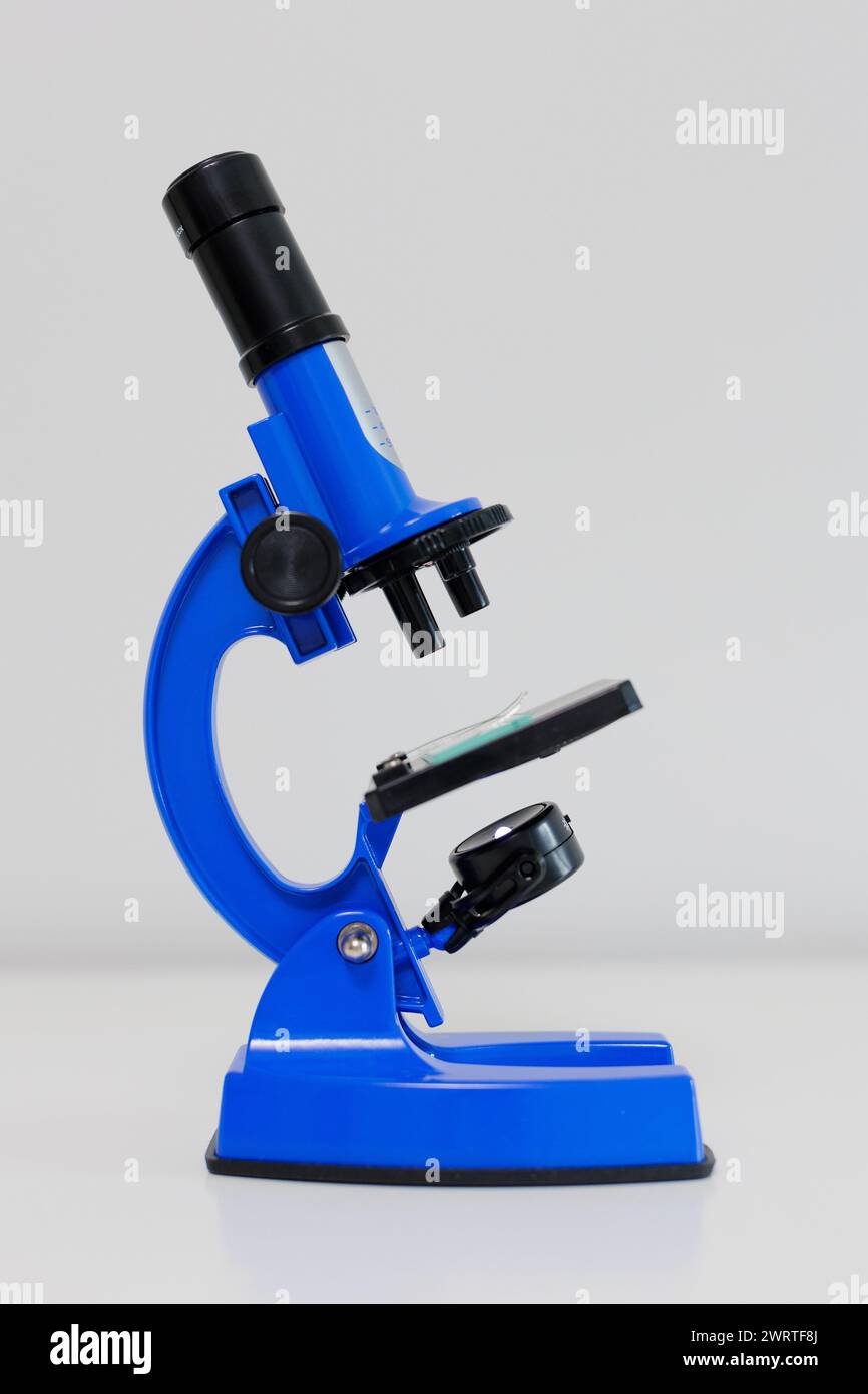 Side view of blue microscope on white table Stock Photo - Alamy