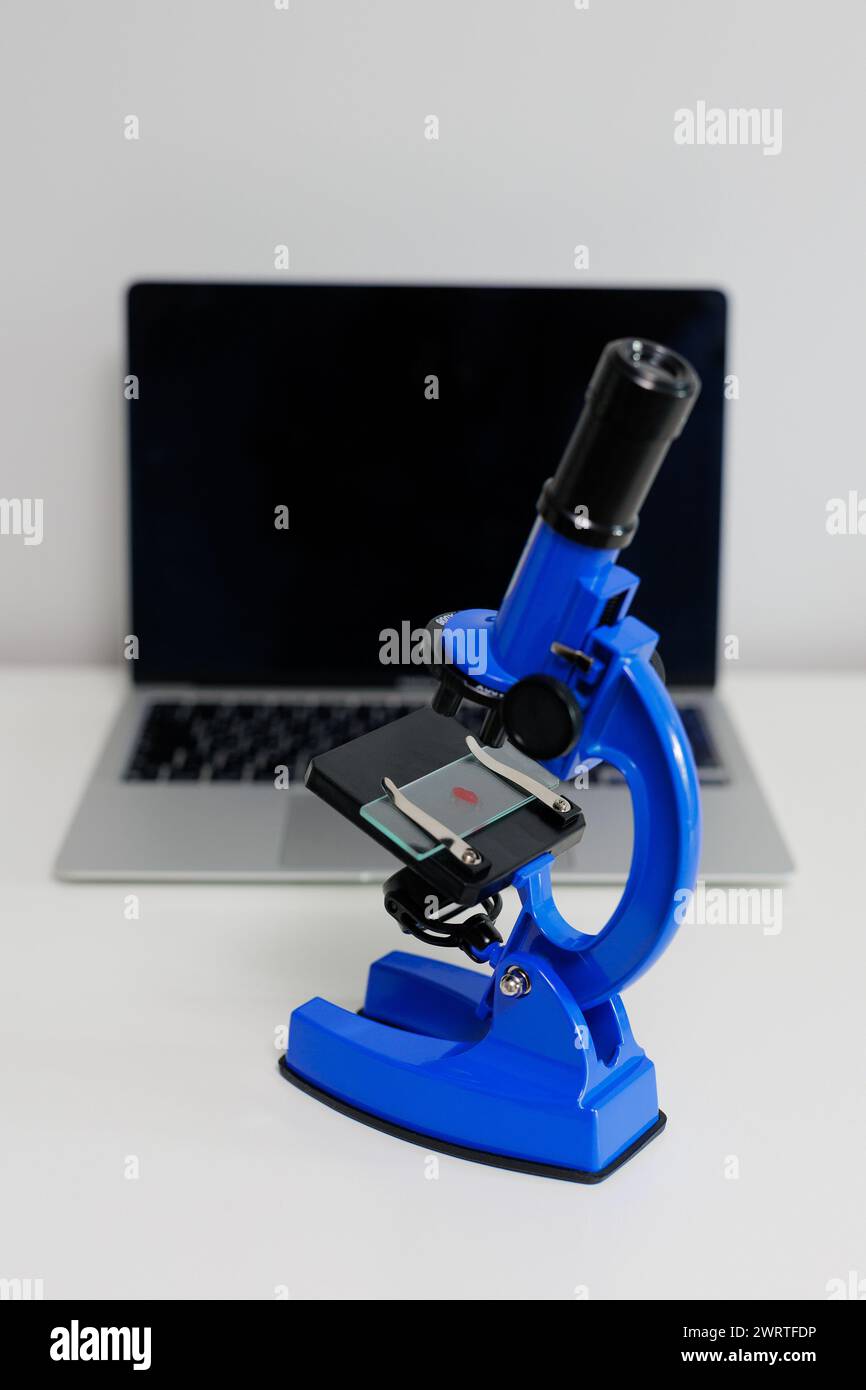 Computer with black screen and blue microscope on white table Stock ...
