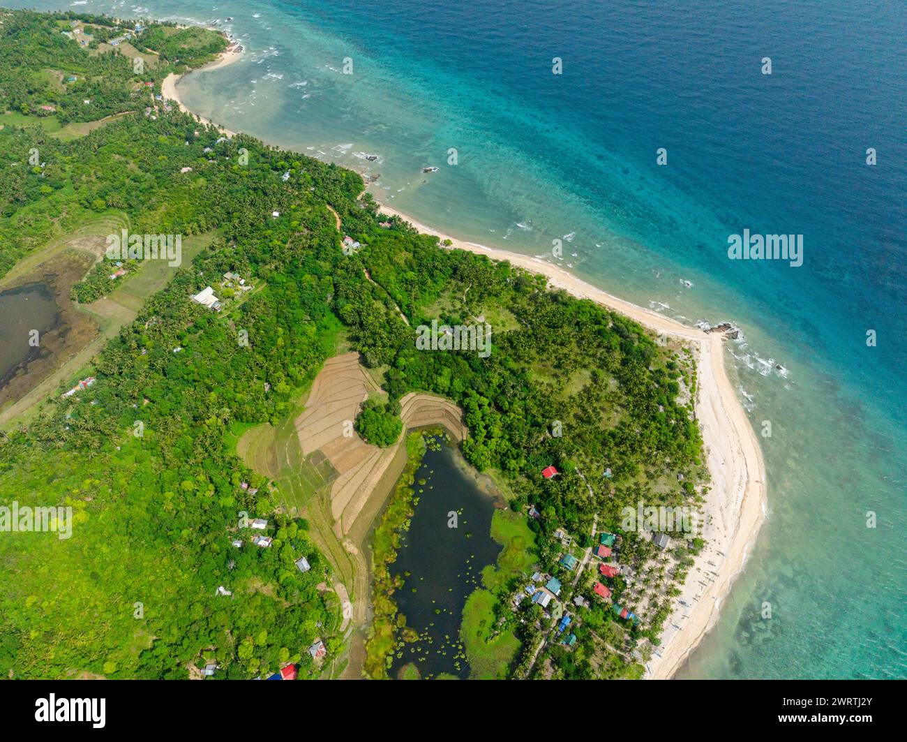 Flying over the houses and white sandy beach in Santa Fe, Tablas ...
