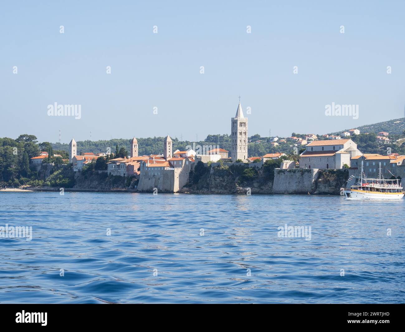 Excursion boat in front of the town of Rab in the morning light, church ...
