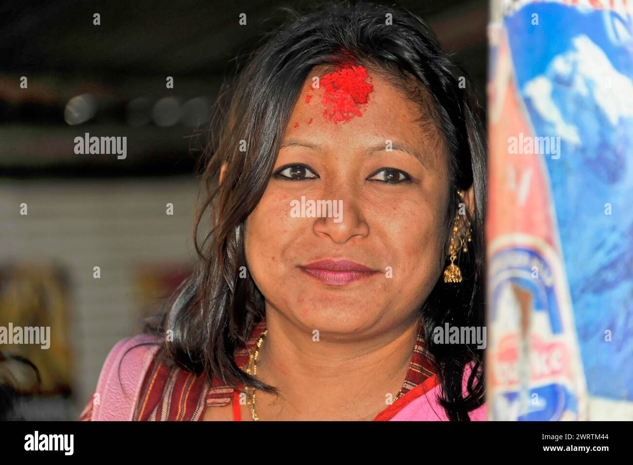 A carefree woman looks directly into the camera, with a red bindi on ...