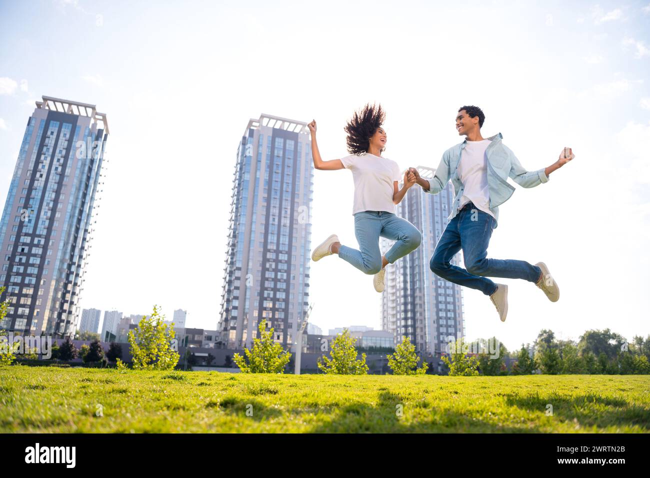 Photo of young happy smiling couple jump active together holding arms ...