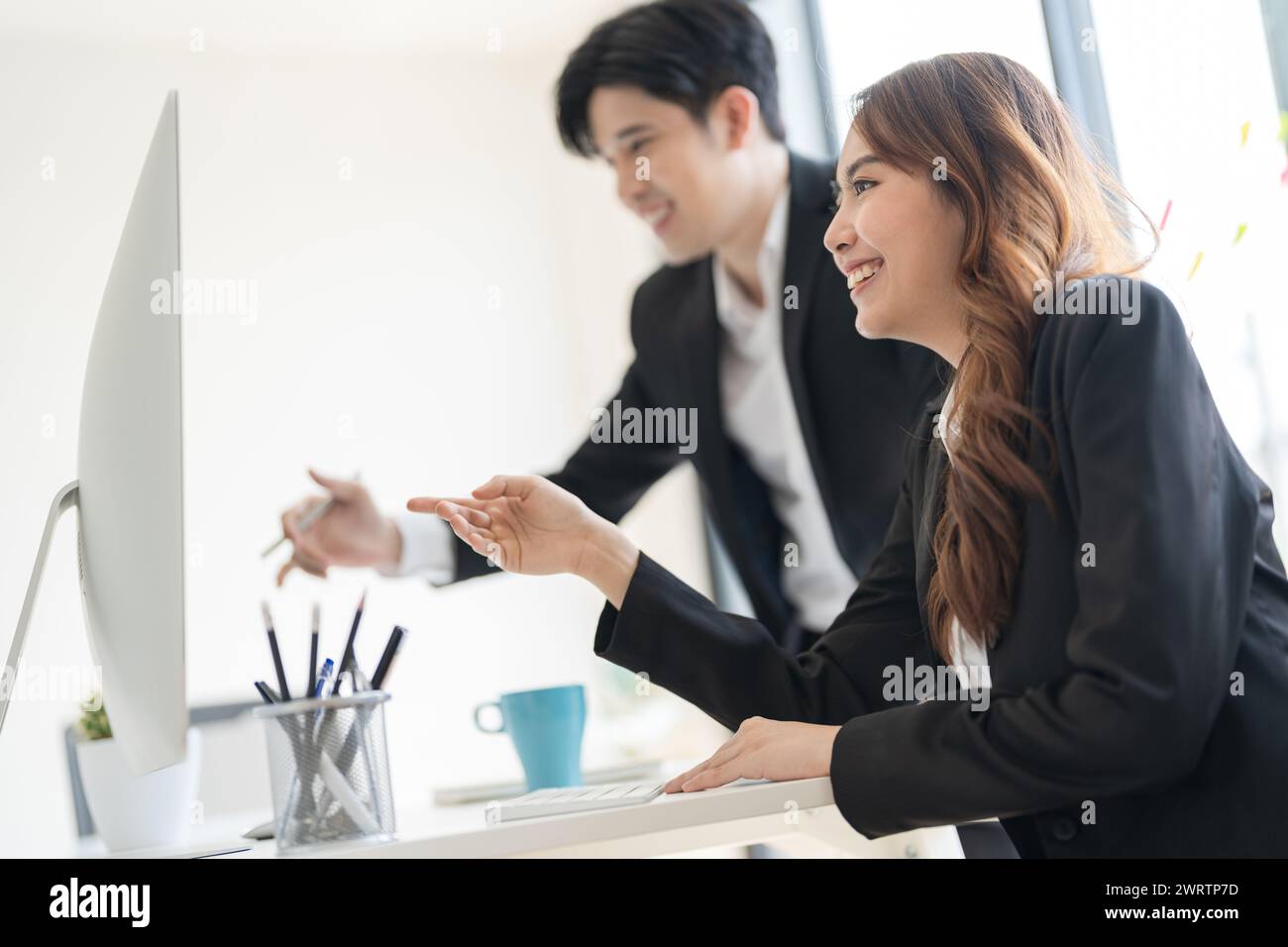 Business people sitting together at a desk using laptops in the office ...