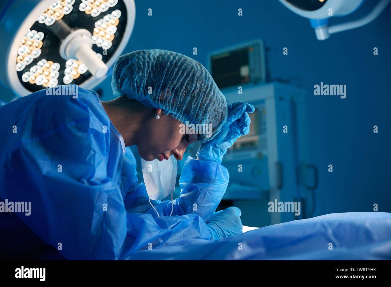 Female surgeon standing in operating room being exhausted and tired ...