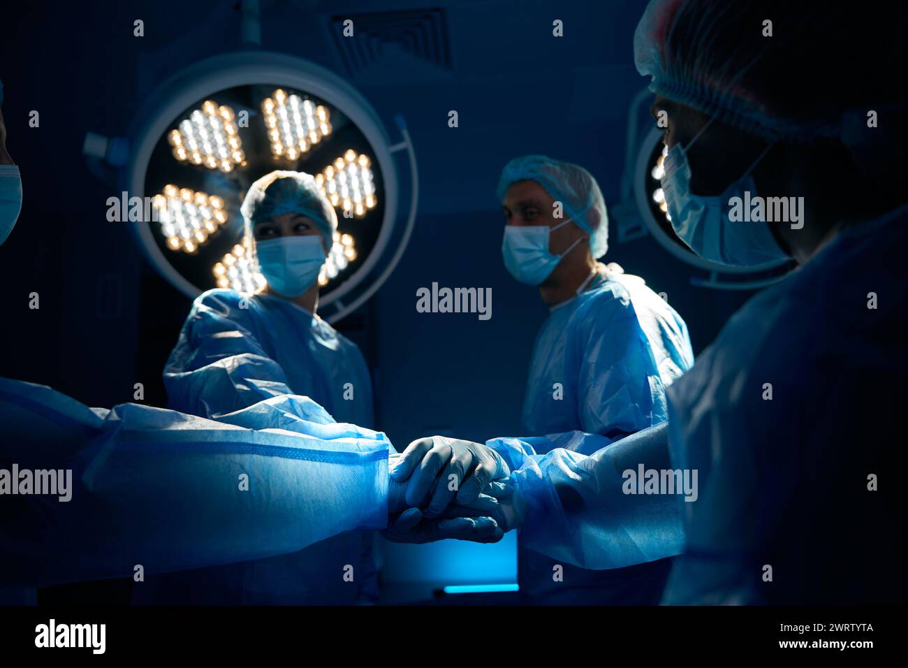 Doctors surgeons team holding hands before the surgery in operating ...