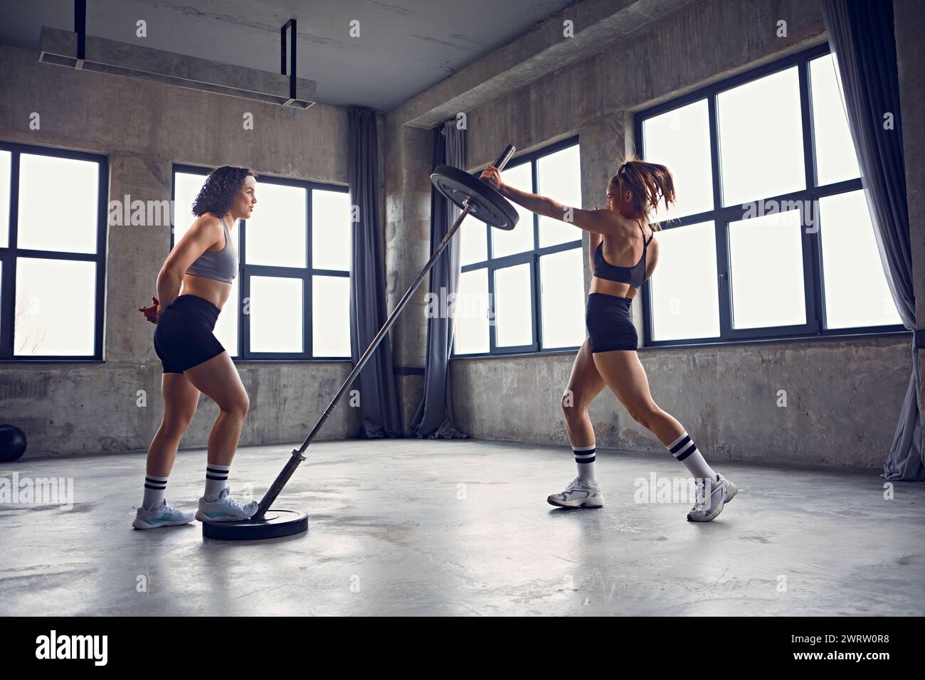 Focused athlete women doing rotational landmine press exercise in ...