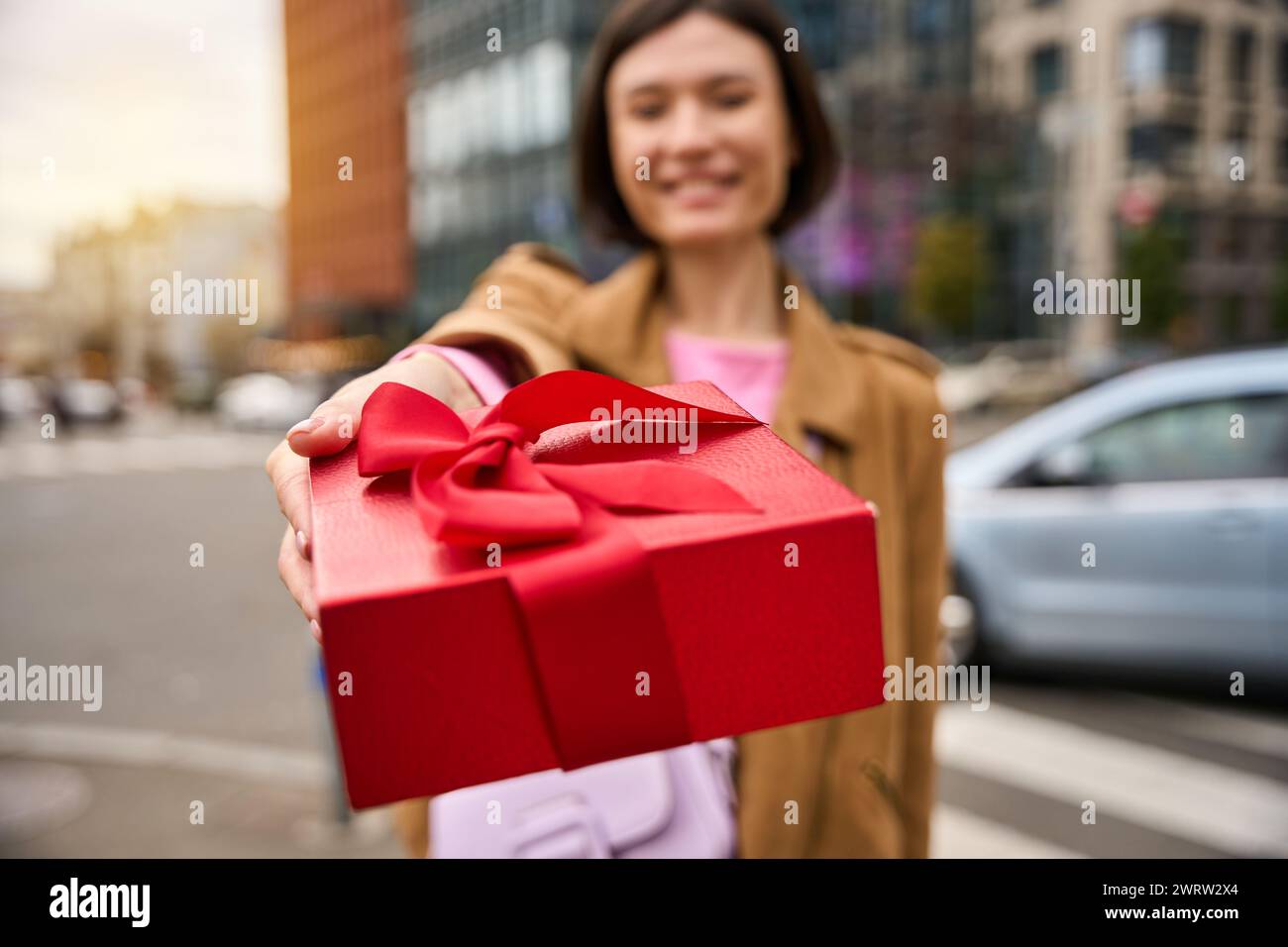 Happy pretty woman giving red present box Stock Photo - Alamy