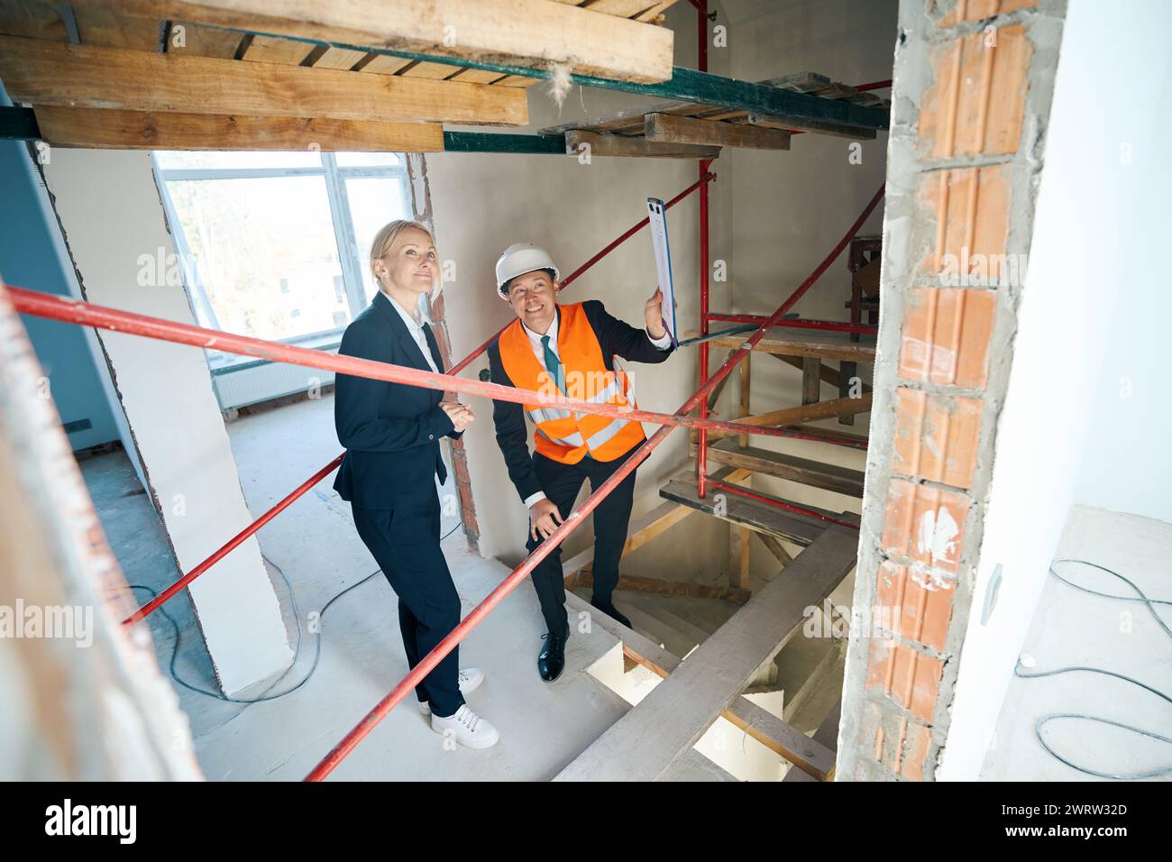 Full length photo of amused businesswoman and smiling construction ...