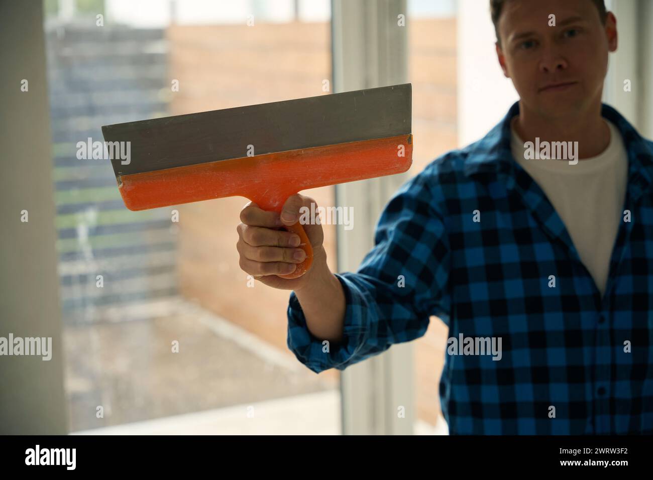 Close up picture of workman standing in room and holding spatula in ...