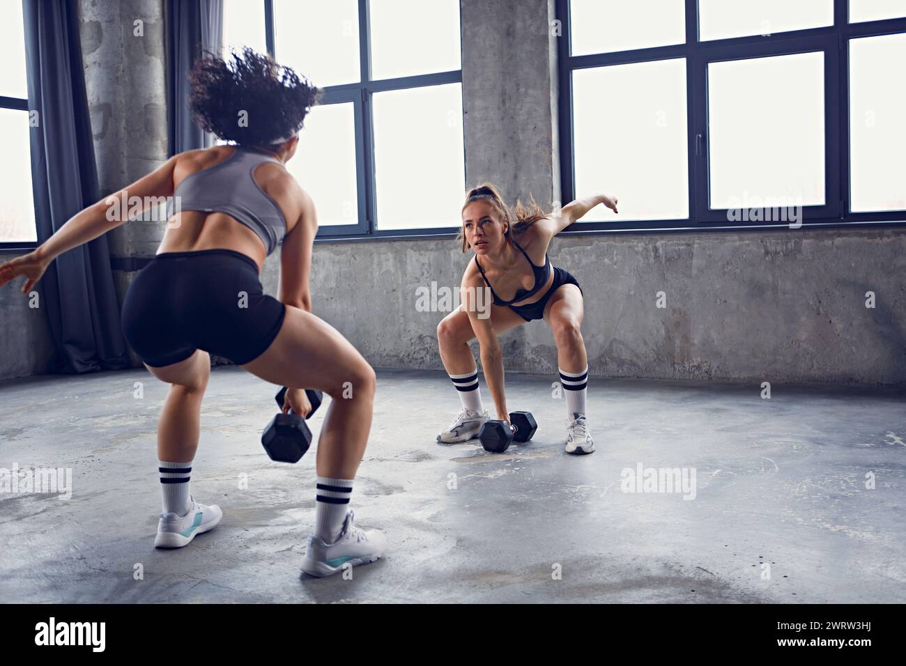 Workout female partners doing squat routine with barbell in motion ...