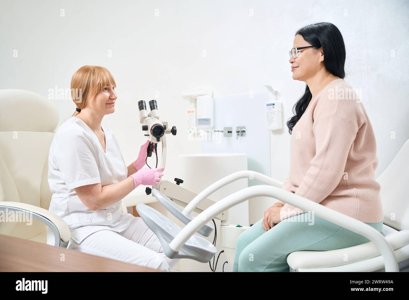 Experienced gynecologist talking with adult asian patient about her ...