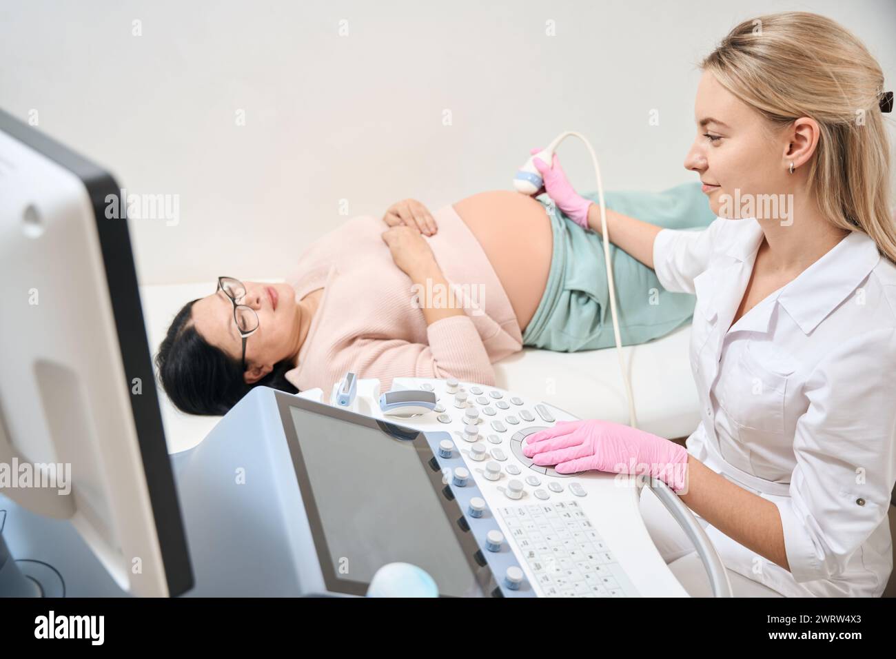 Smiling woman gynecologist making ultrasound of woman on second ...