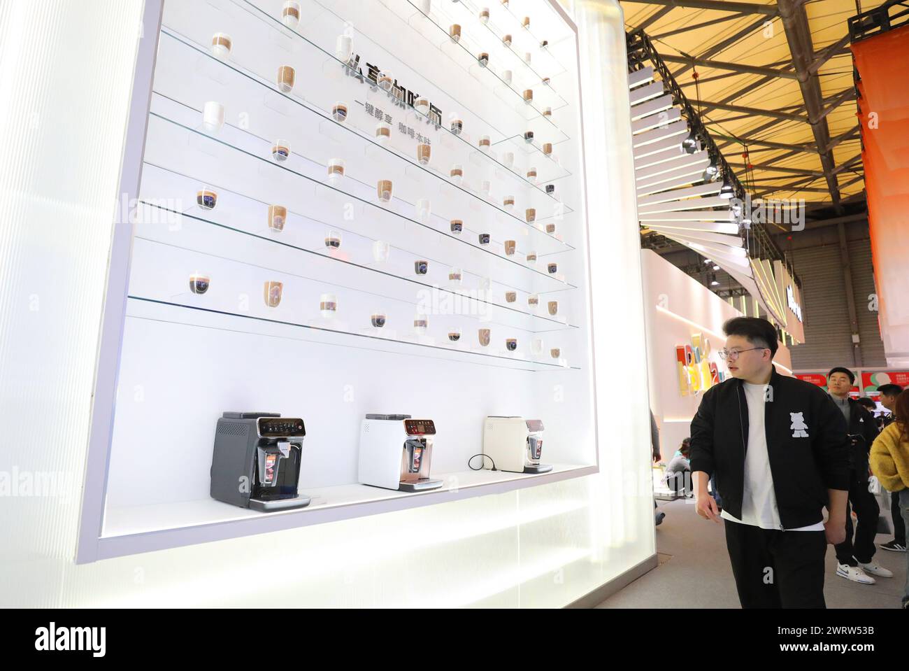 Shanghai. 14th Mar, 2024. A visitor walks past the display wall of ...
