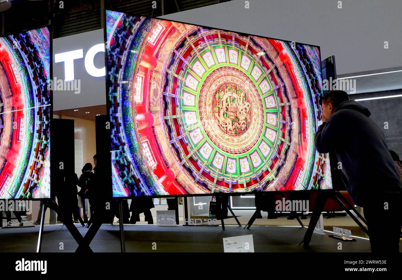 Shanghai. 14th Mar, 2024. A visitor looks at the screen of a TV at TCL's booth during the 2024 ...
