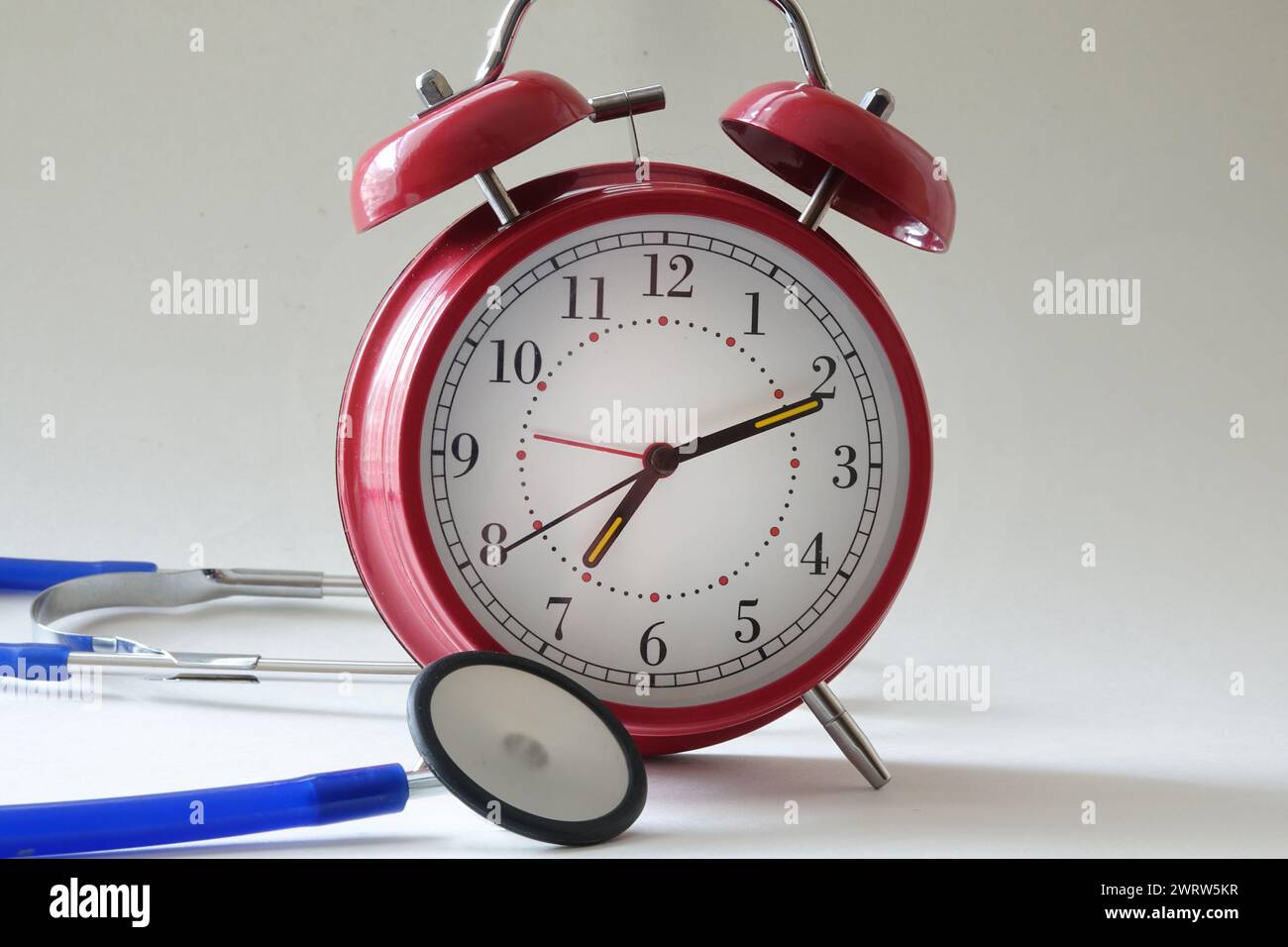 Stethoscope next to clock on white table Stock Photo - Alamy