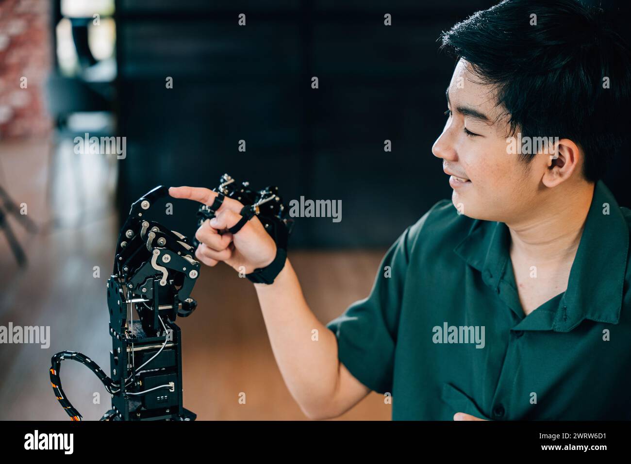 Enthusiastic Asian teen boy learns technology by testing a robot hand ...