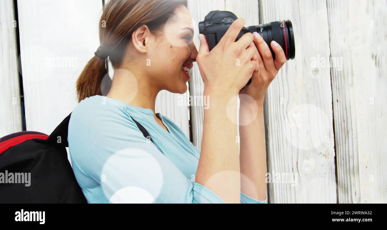 White spots floating against caucasian female photographer clicking ...