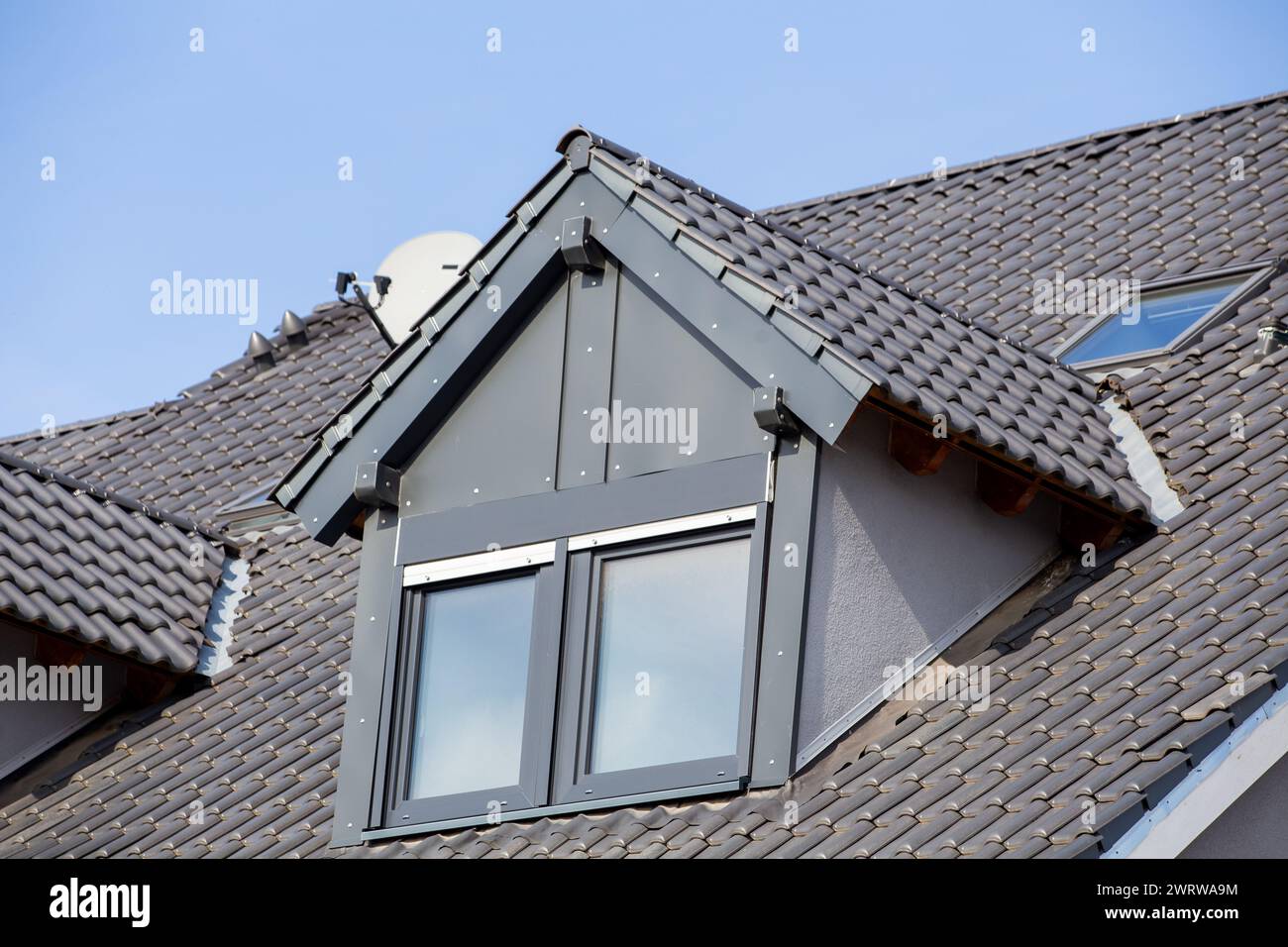 Dormer window on a tiled roof, clad with titanium zinc on the front ...