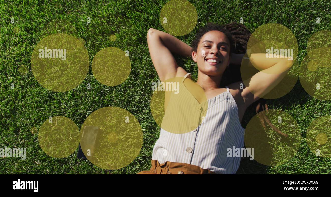 Image of yellow spots over smiling biracial woman lying in park Stock ...