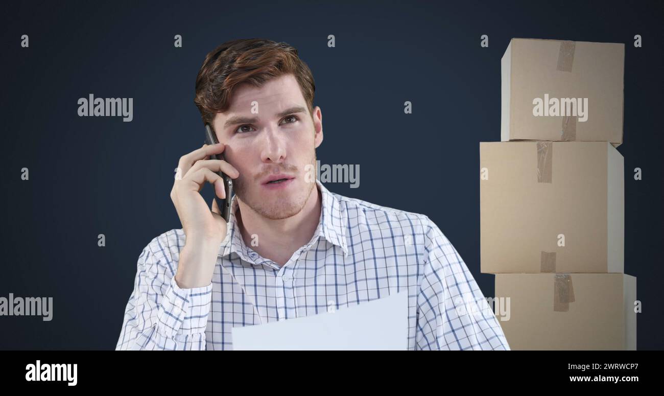 Image of man talking on smartphone with stack of boxes on blue ...