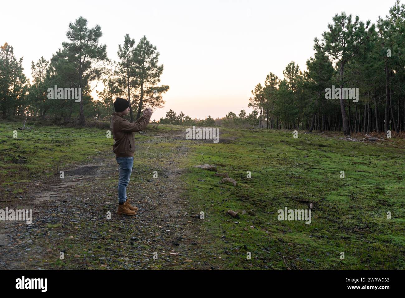 Man standing alone in the forest taking a photo with his mobile phone ...