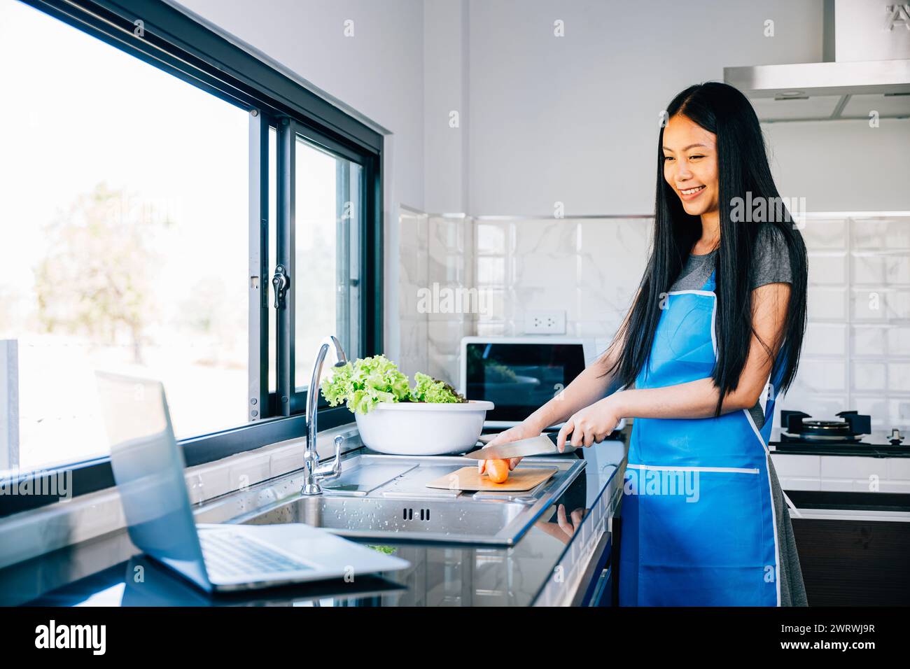 A woman stands in the kitchen enjoying cooking while searching for ...