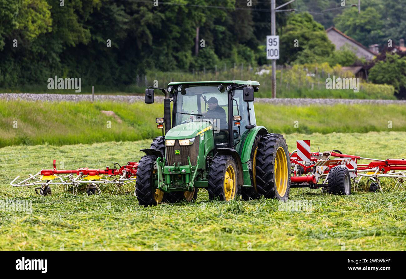 Ein Bauer fährt mit seinem Traktor John Deere 5085M auf einer Wiese wo ...