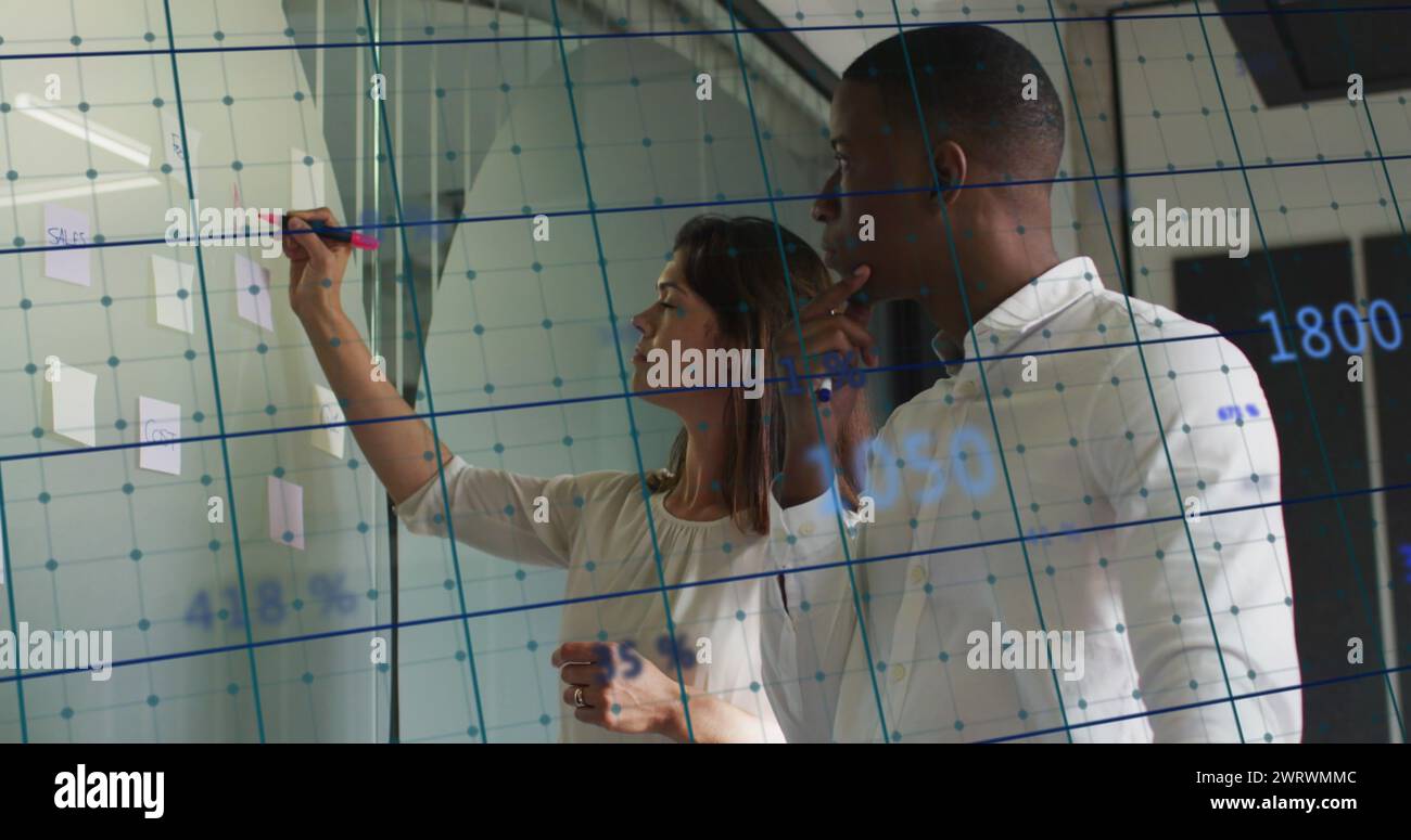 We are a diverse group of businesspeople writing on a whiteboard in a ...