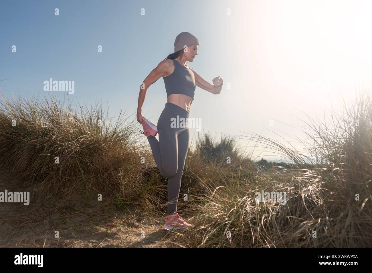 fit sporty woman checking her smart watch while doing leg stretching ...