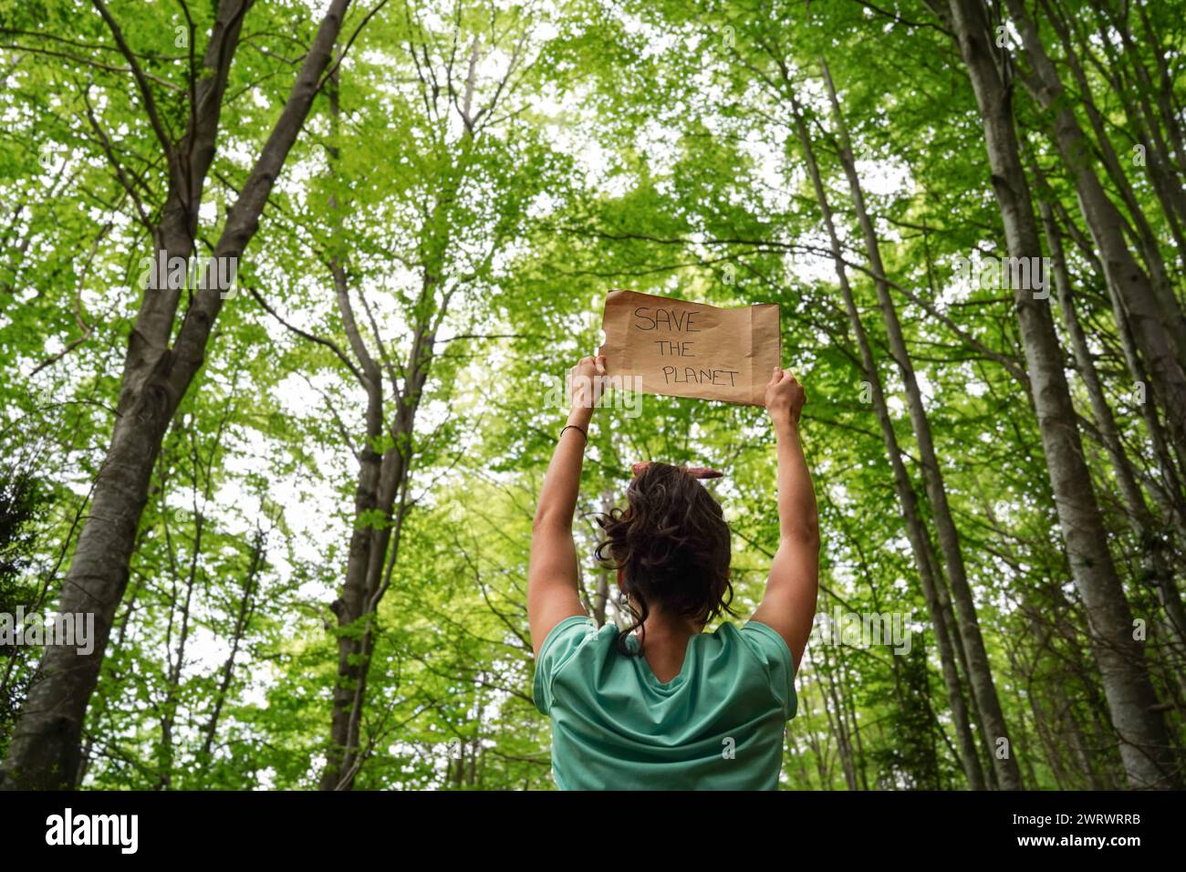 A woman is holding a sign that says "save the planet" .Stop the ...