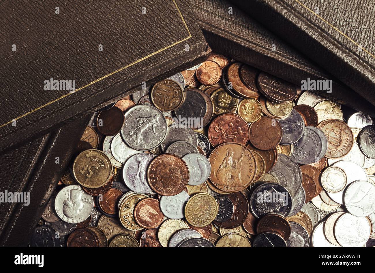 Photo of antique old books laying on scattered pile of world coins ...