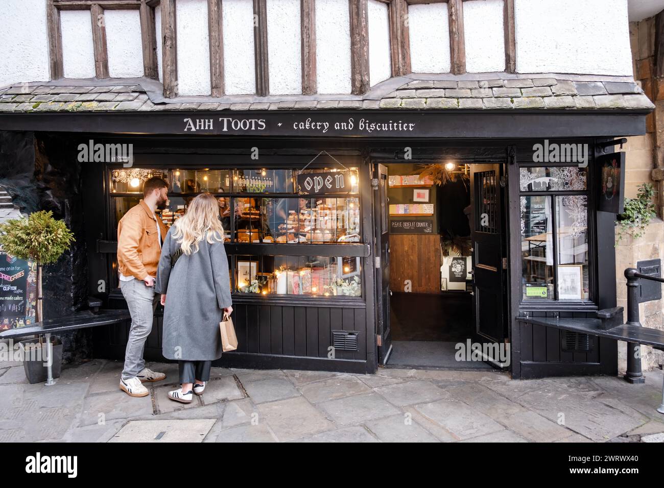 Bristol, UK. A male and female couple stop outside a Tudor fronted cake ...