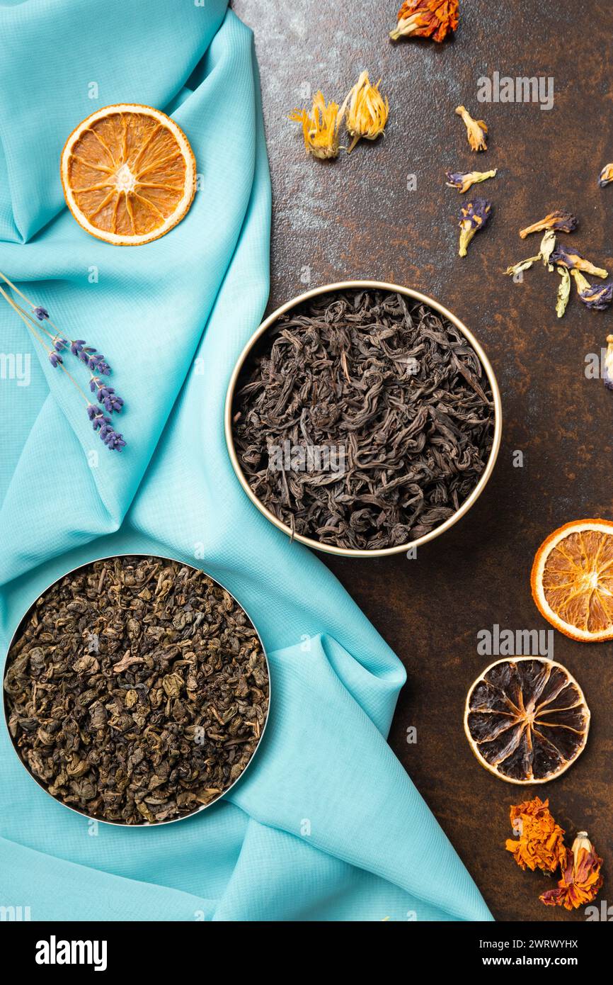 Composition of black, green, flower tea and dried orange slices on blue ...