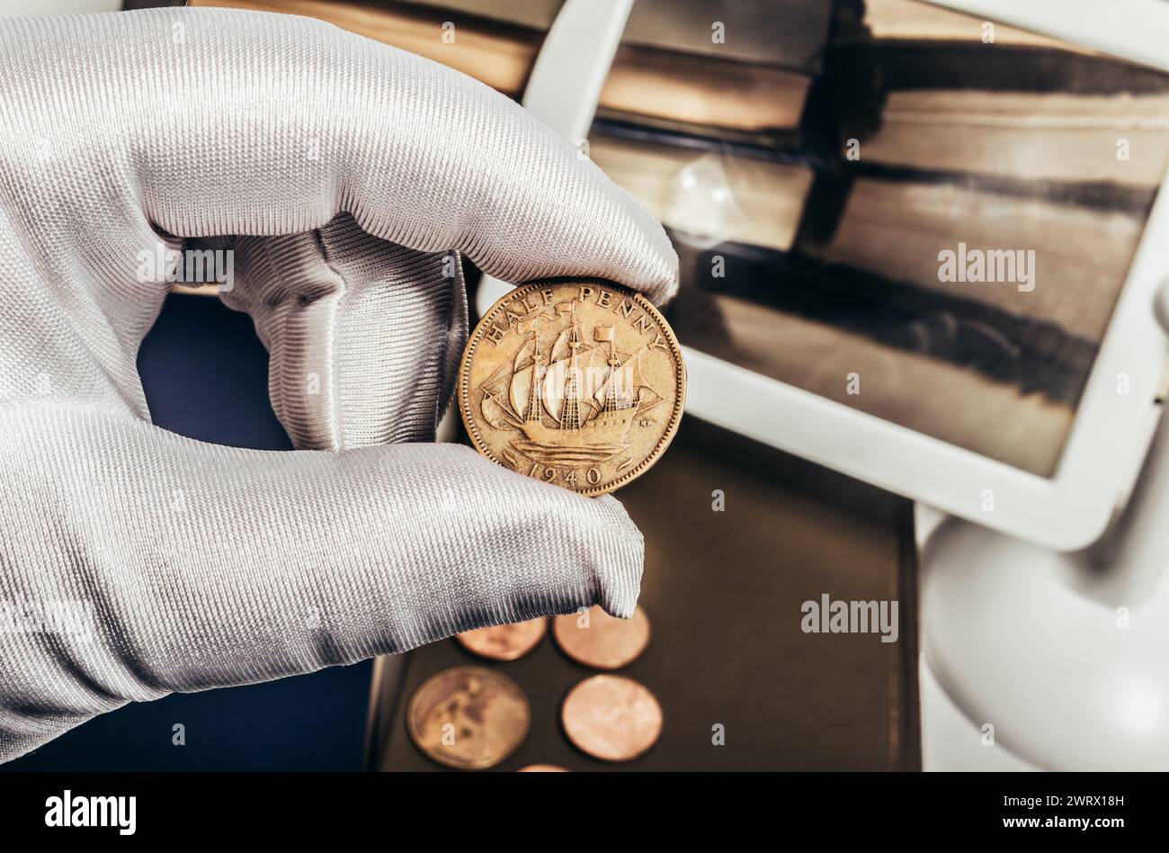 Photo of a person's male hand in white gloves holding a 1940 half penny ...