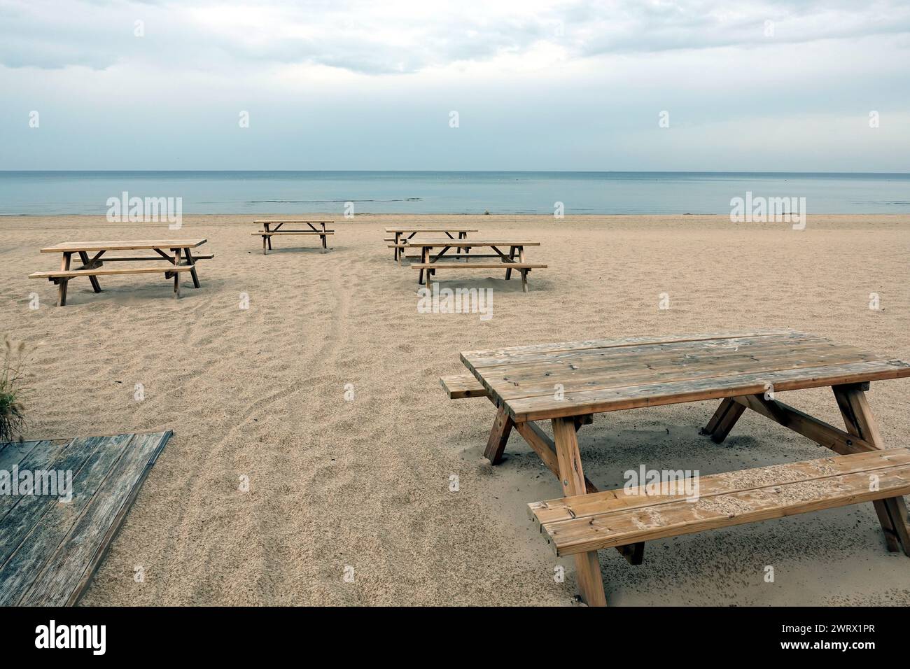 Several wooden tables and benches on empty sandy beach in Jurmala ...