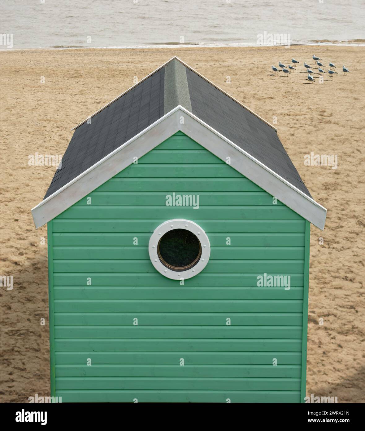 A single wooden in beach hut with round window, beach and sea, with ...