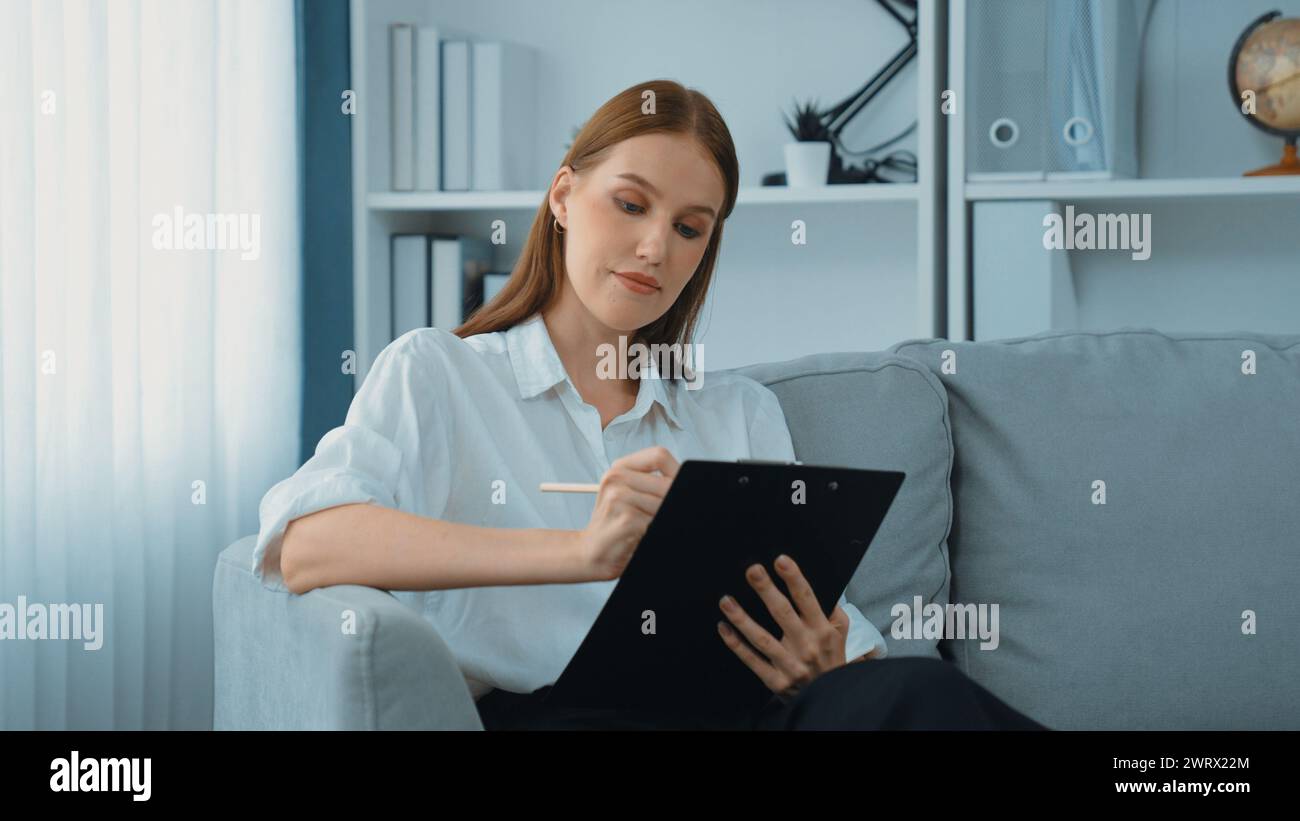 Professional female psychologist with clipboard portrait sitting on arm ...