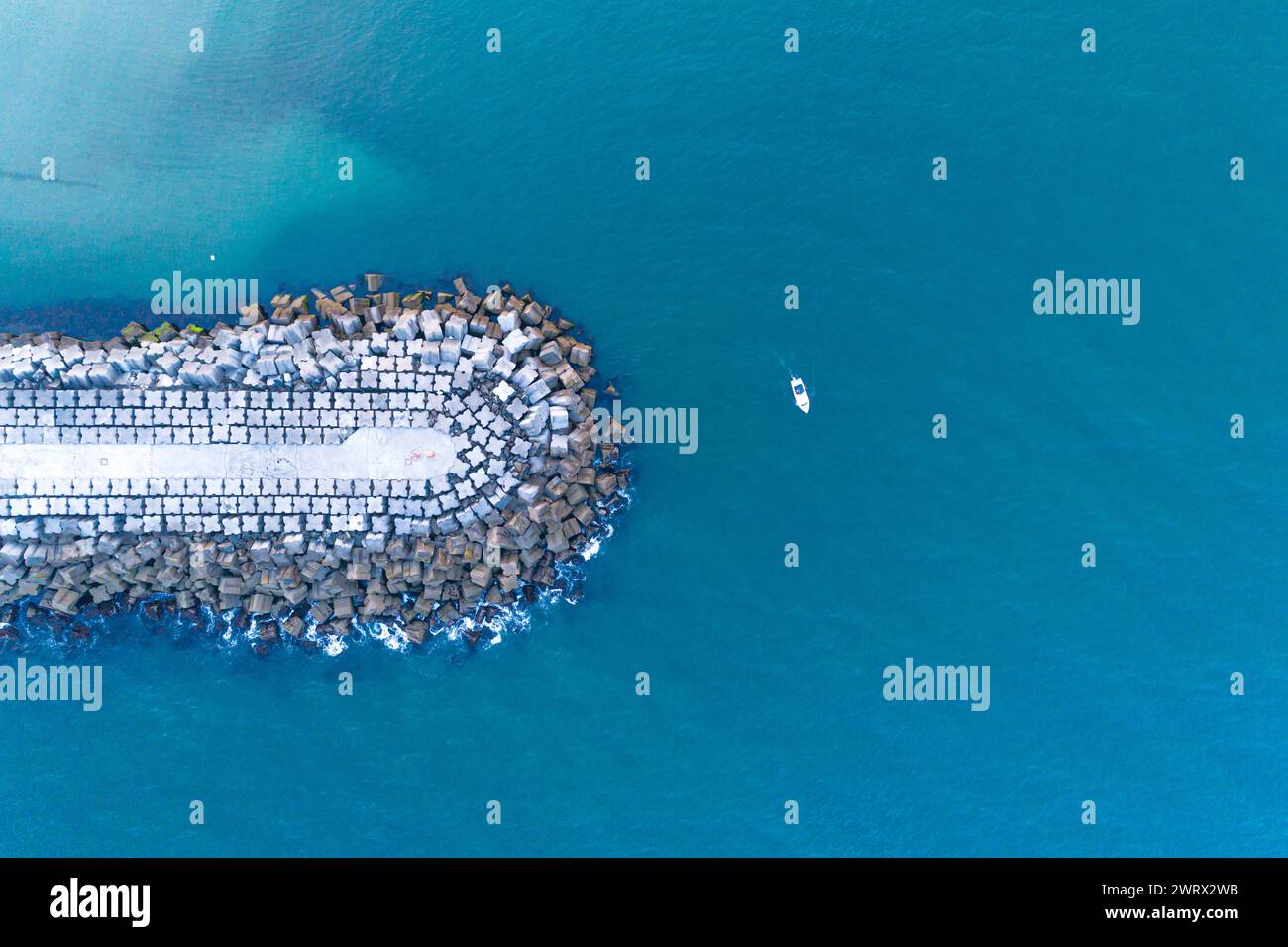 ship sailing near the breakwater of a harbor, top view from a drone ...