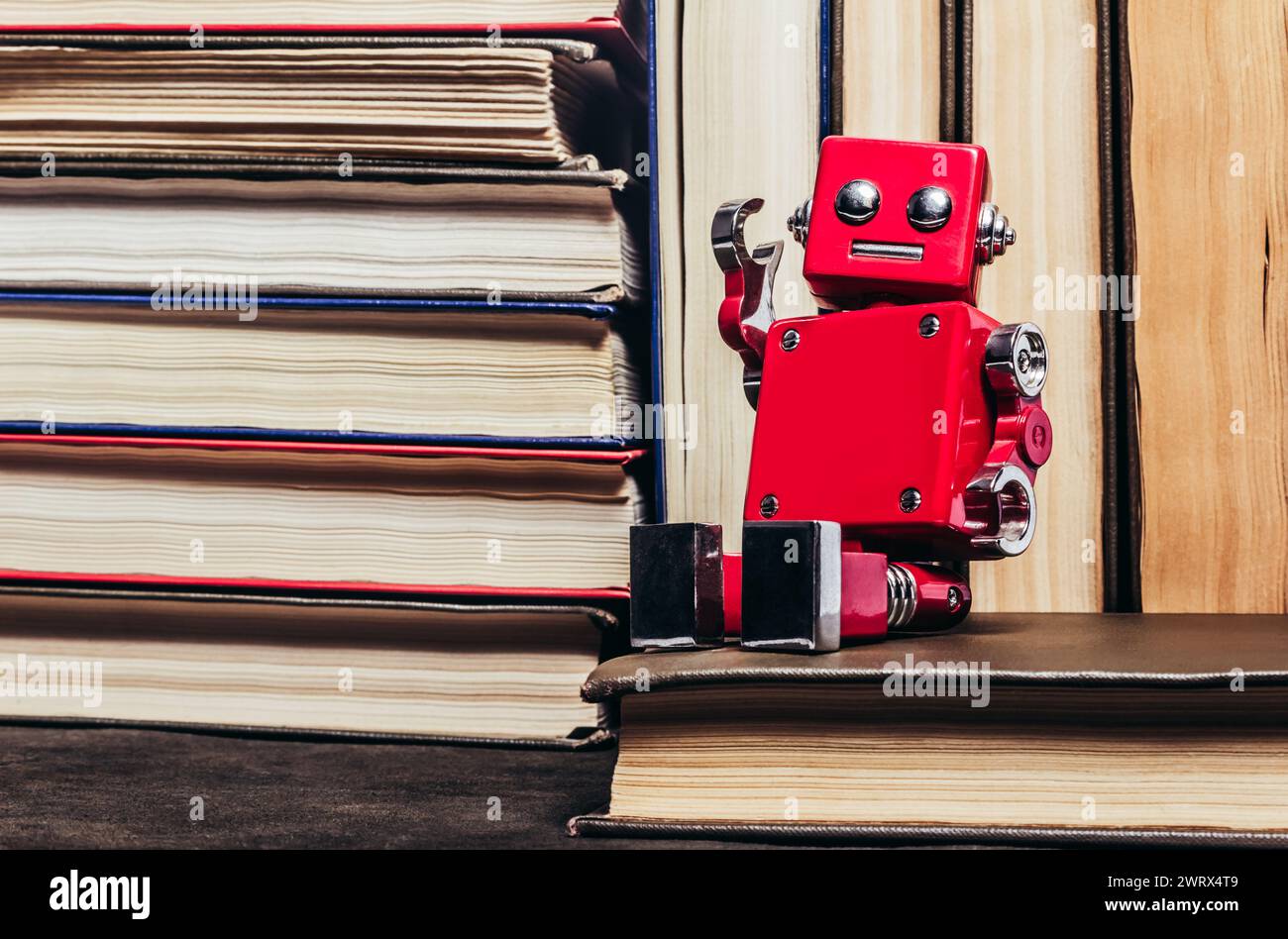 Photo of old antique books stack and row with sitting red robot toy ...