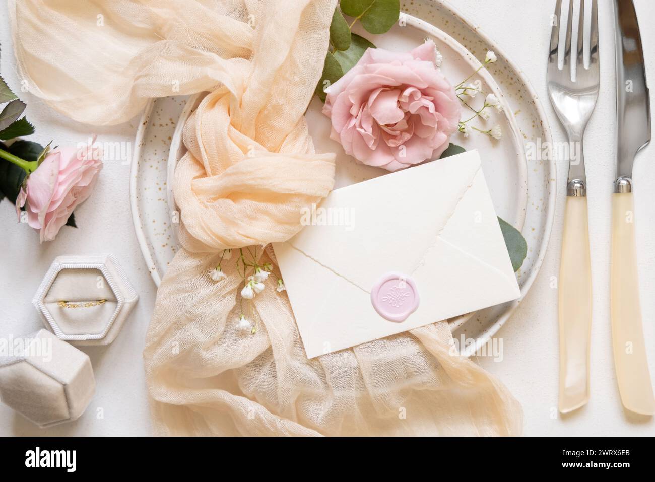 Sealed envelope near cream tulle fabric knot and light pink roses on ...