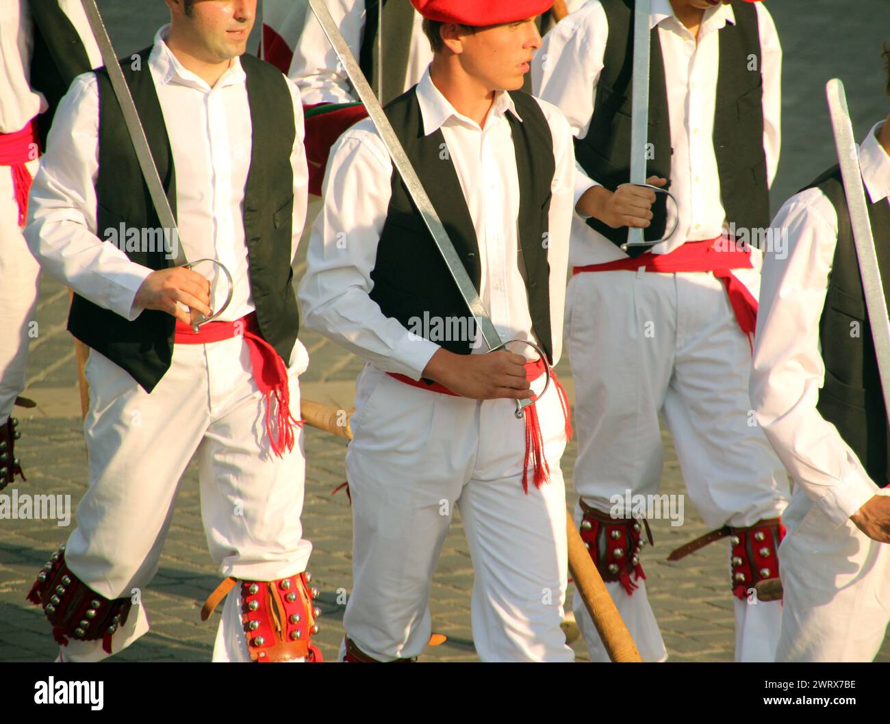 Three adult males wearing vests and hats, standing in a field with two ...