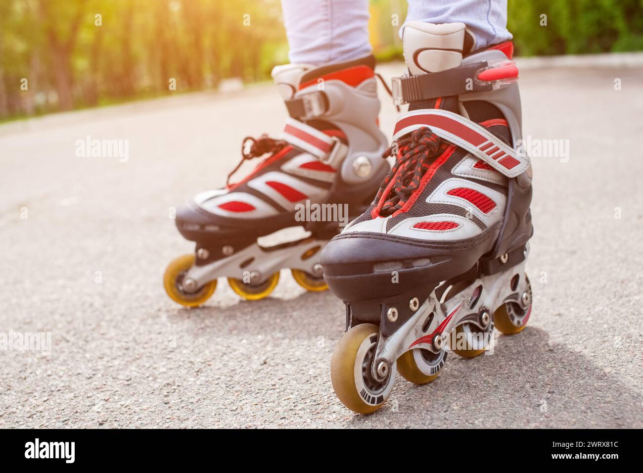 Girl teenager rollerblading on the asphalt in the park, legs close-up ...