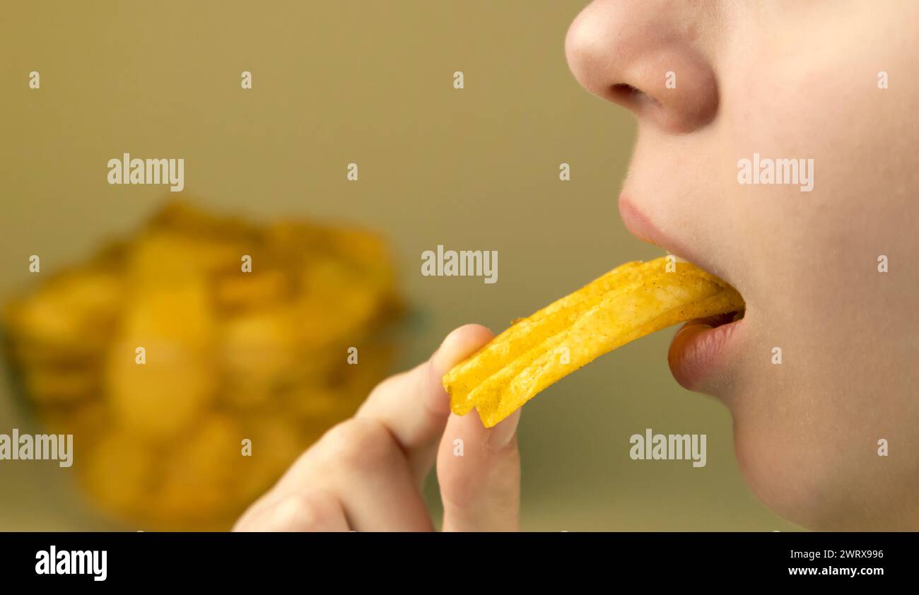 Close-up portrait of a teenage girl eating potato chips, The concept of ...