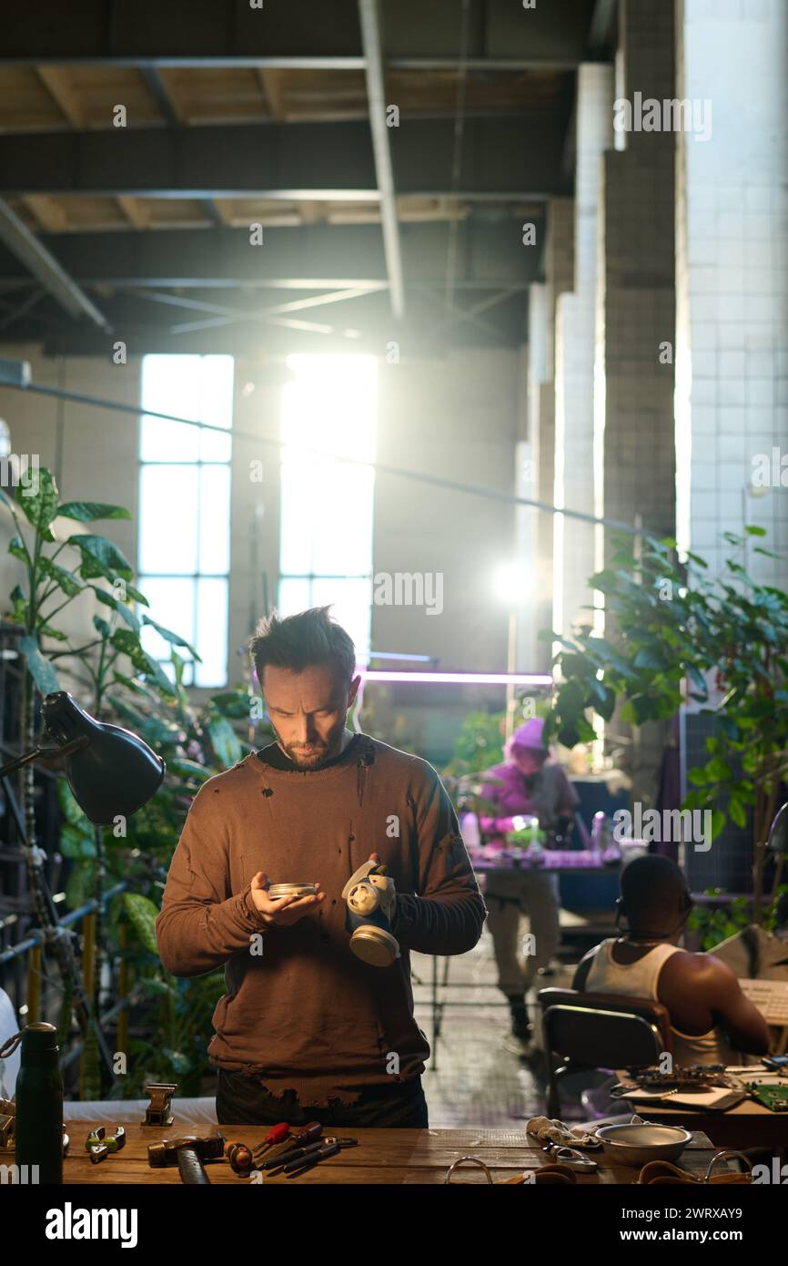 Vertical shot of Caucasian man wearing distressed sweater repairing old ...