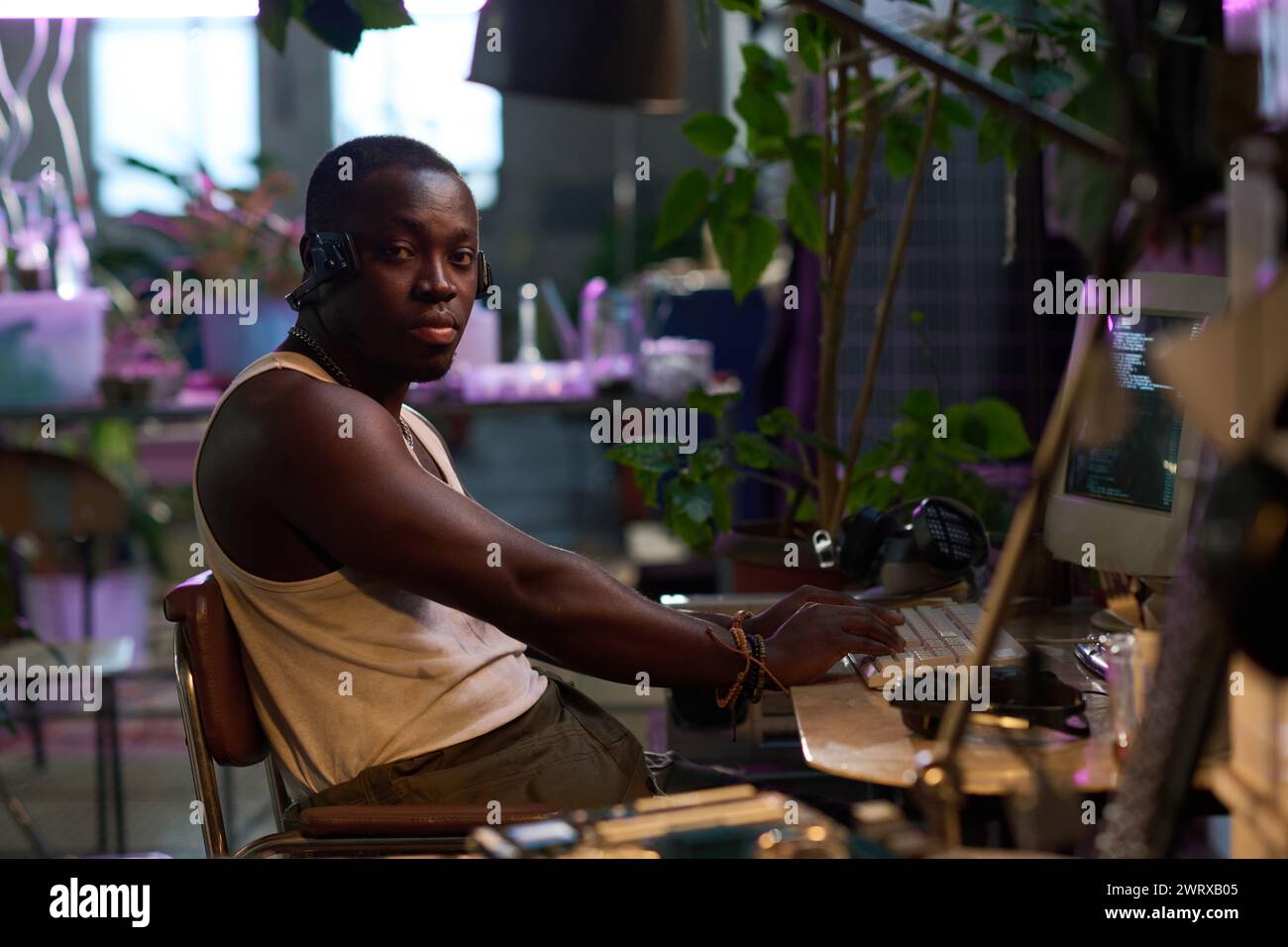 Young African American programmer sitting at desk in shelter working on ...