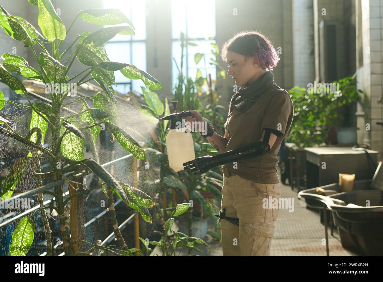 Medium long shot of young woman with prosthetic arm taking care of ...
