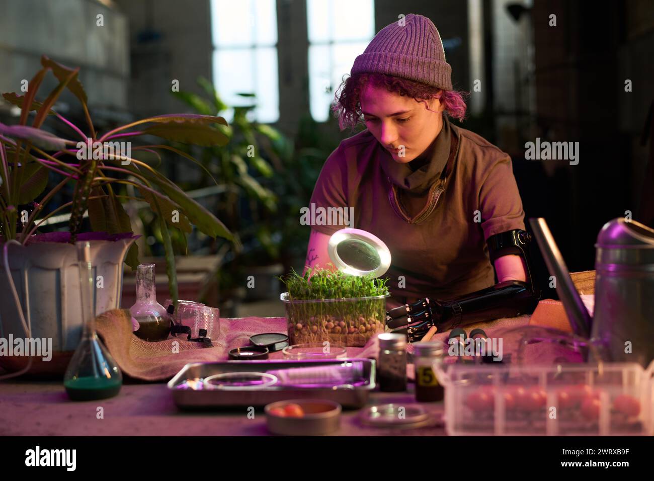 Medium shot of young woman with prosthetic arm growing plants in post ...