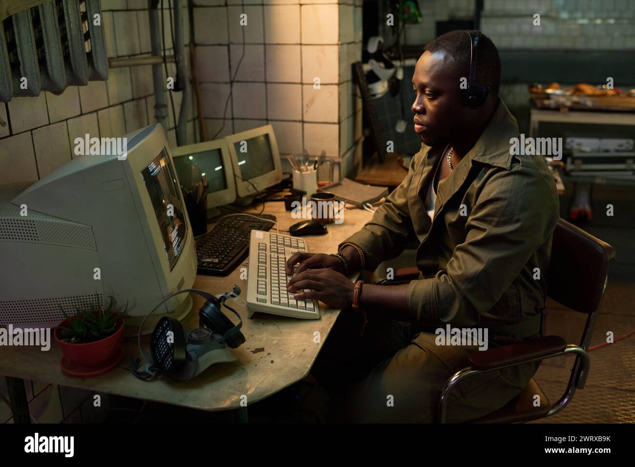 Serious African American IT specialist wearing headphones coding on old ...