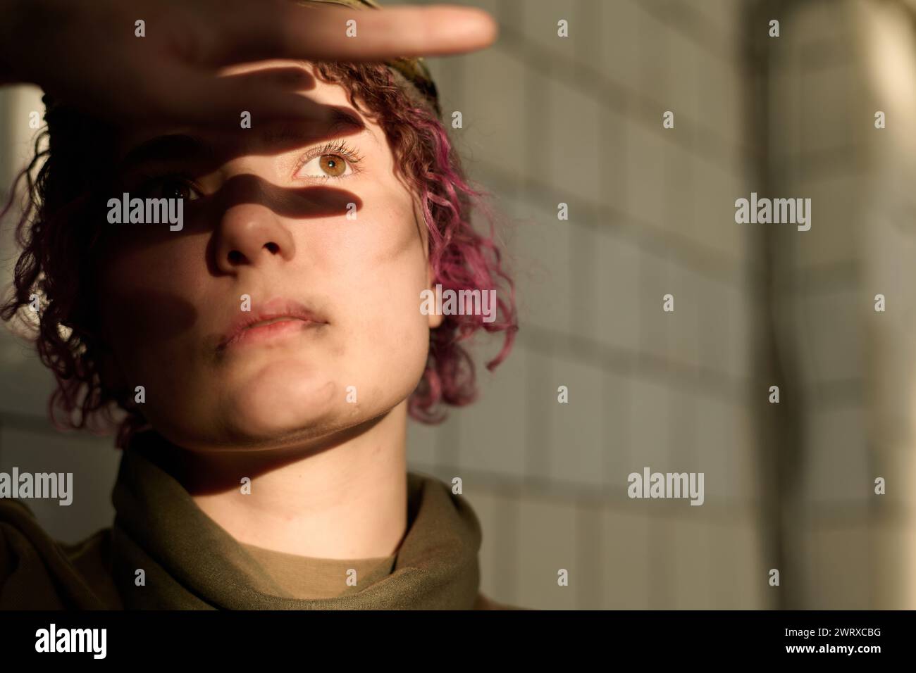 Closeup of young woman with dirt on face covering eyes from sun light ...